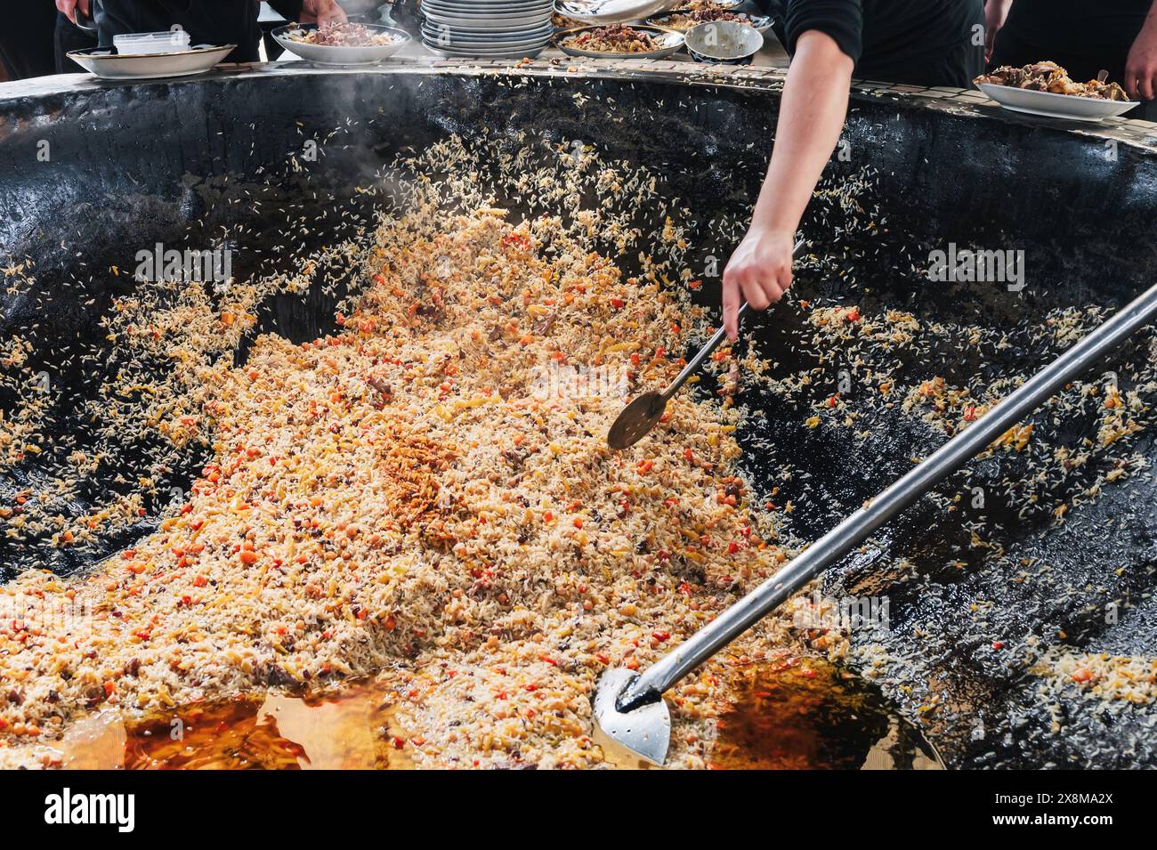hands of a male cooking traditional oriental Arabic Uzbek rice pilaf in ...