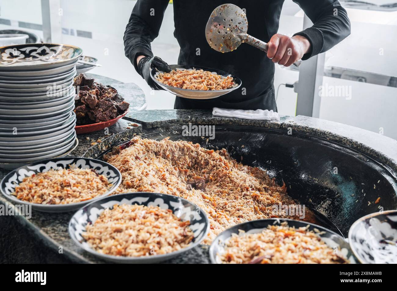 male hands chef cooking traditional oriental Arabic Uzbek pilaf with ...
