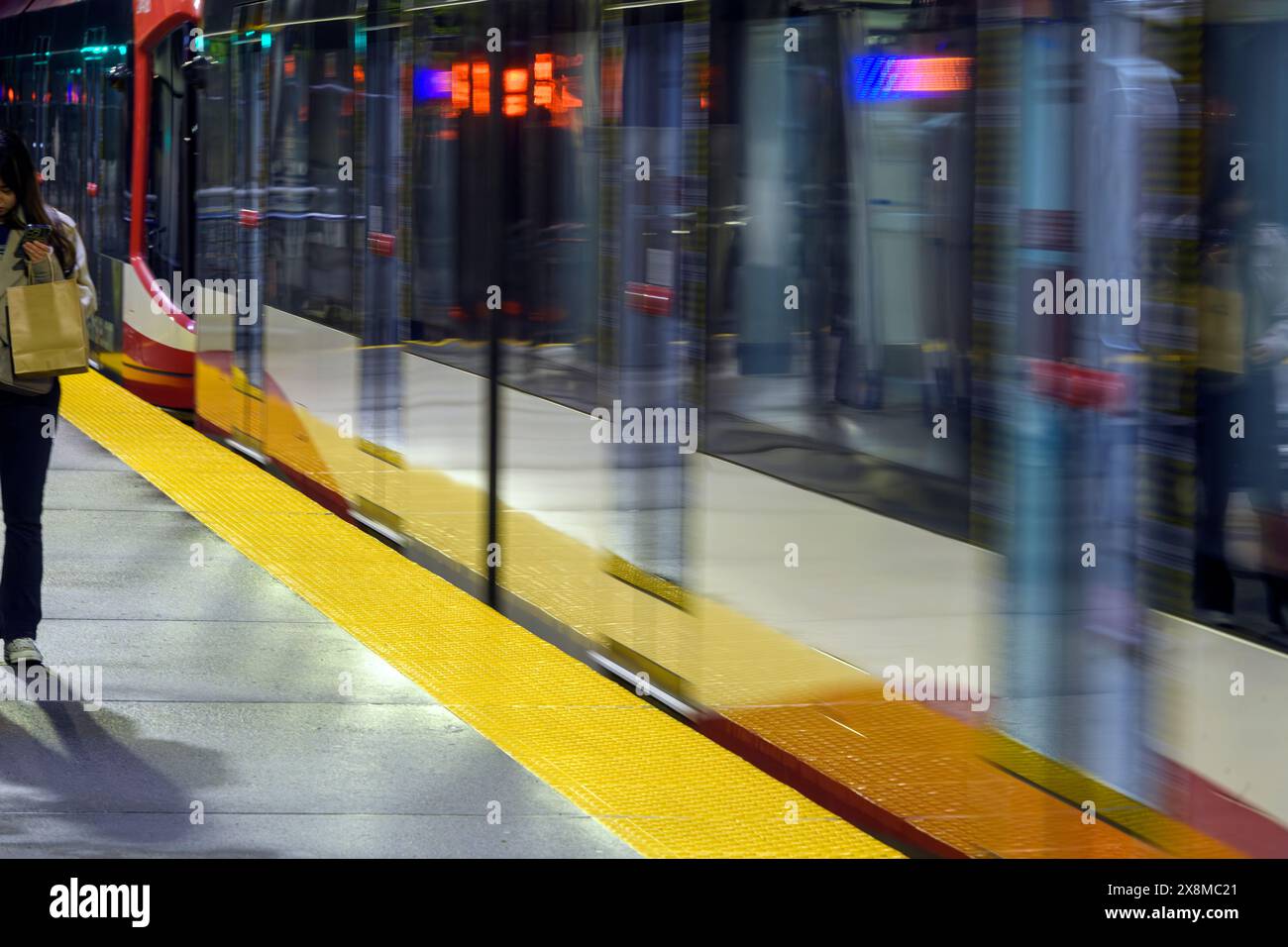 Female at a downtown light rail transit station at night in Calgary ...