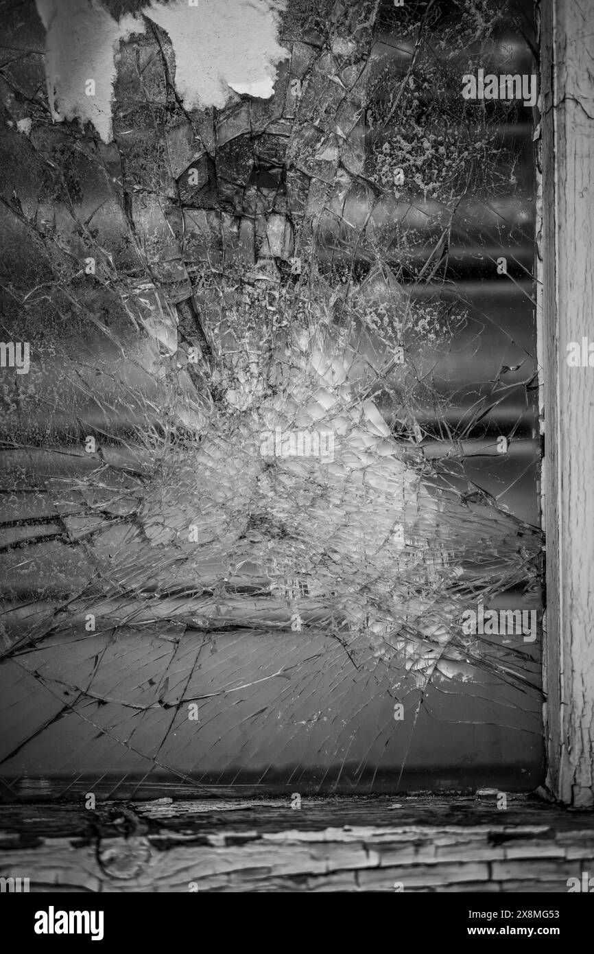 Close-up of a shattered window pane with cracked glass, highlighting ...