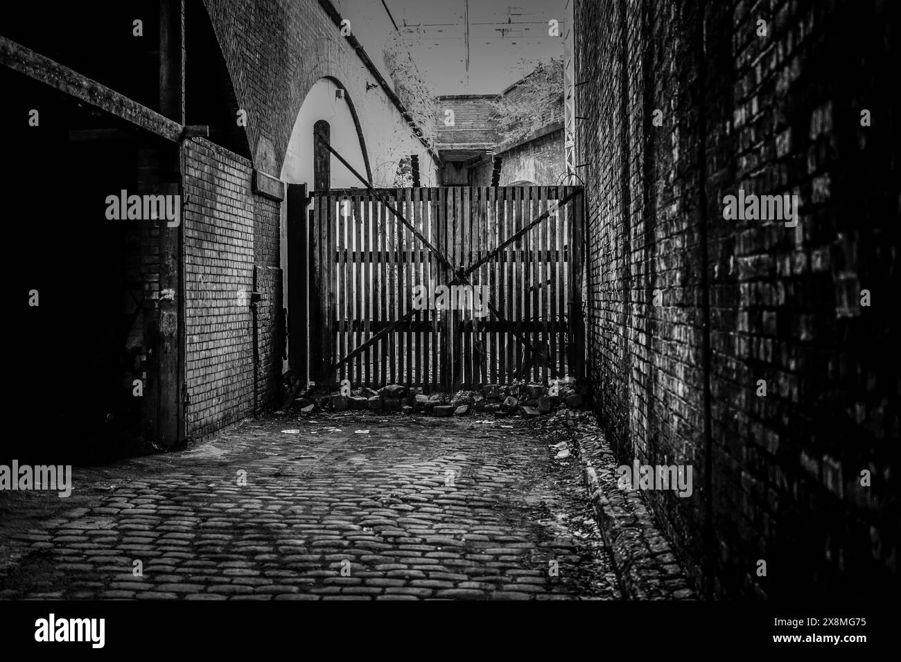 Black and white photo of deserted cobblestone alley with industrial ...