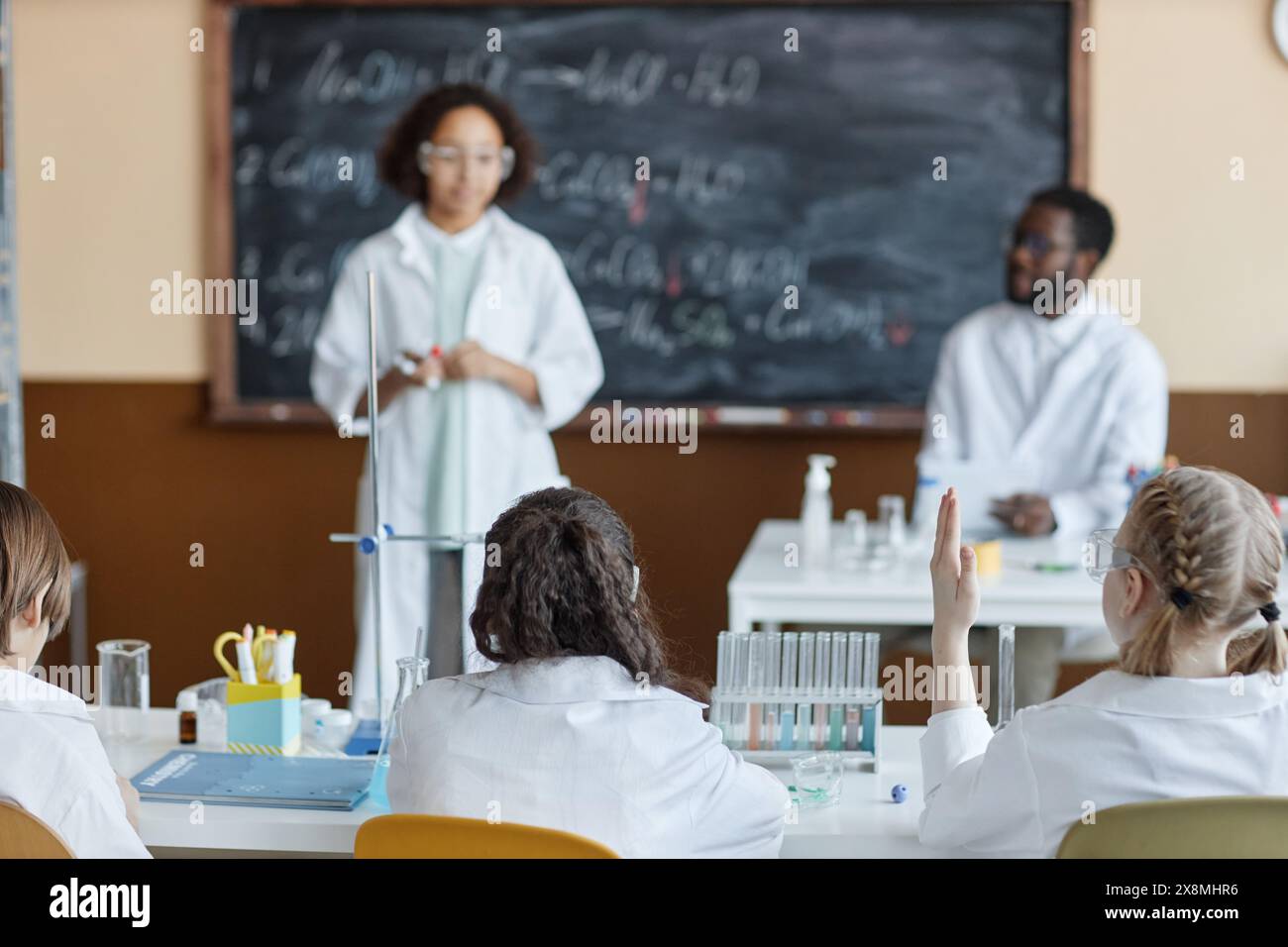 Selective focus shot of middle school students solving problems and raising hands during ...