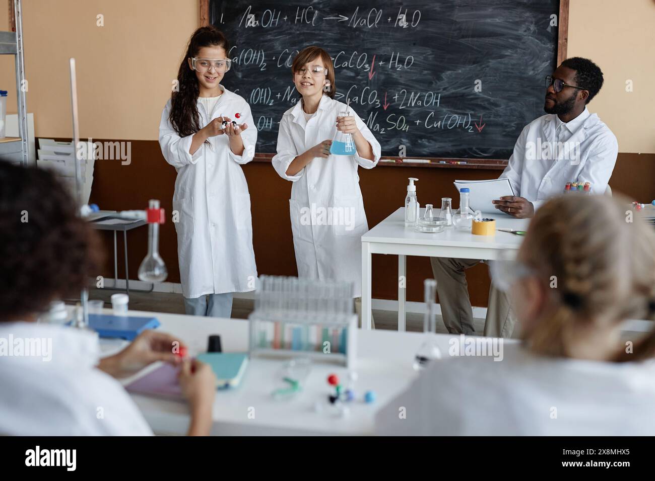 Ethnically diverse boy and girl wearing lab coats and goggles ...