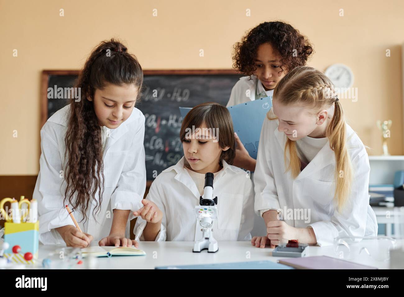 Group of four ethnically diverse boys and girls wearing lab coats ...