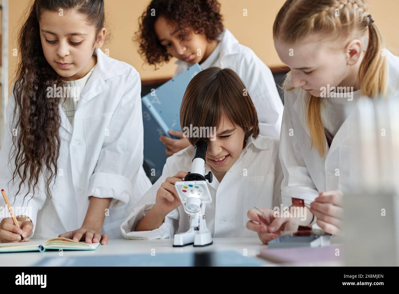 Group of ethnically diverse middle school students wearing lab coats ...