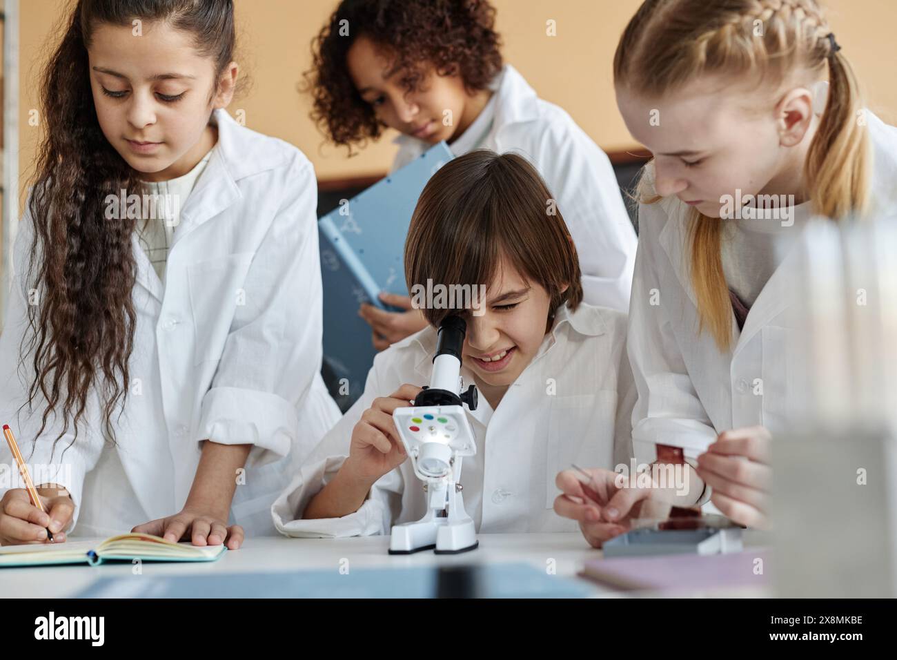 Group of ethnically diverse middle school students wearing lab coats ...