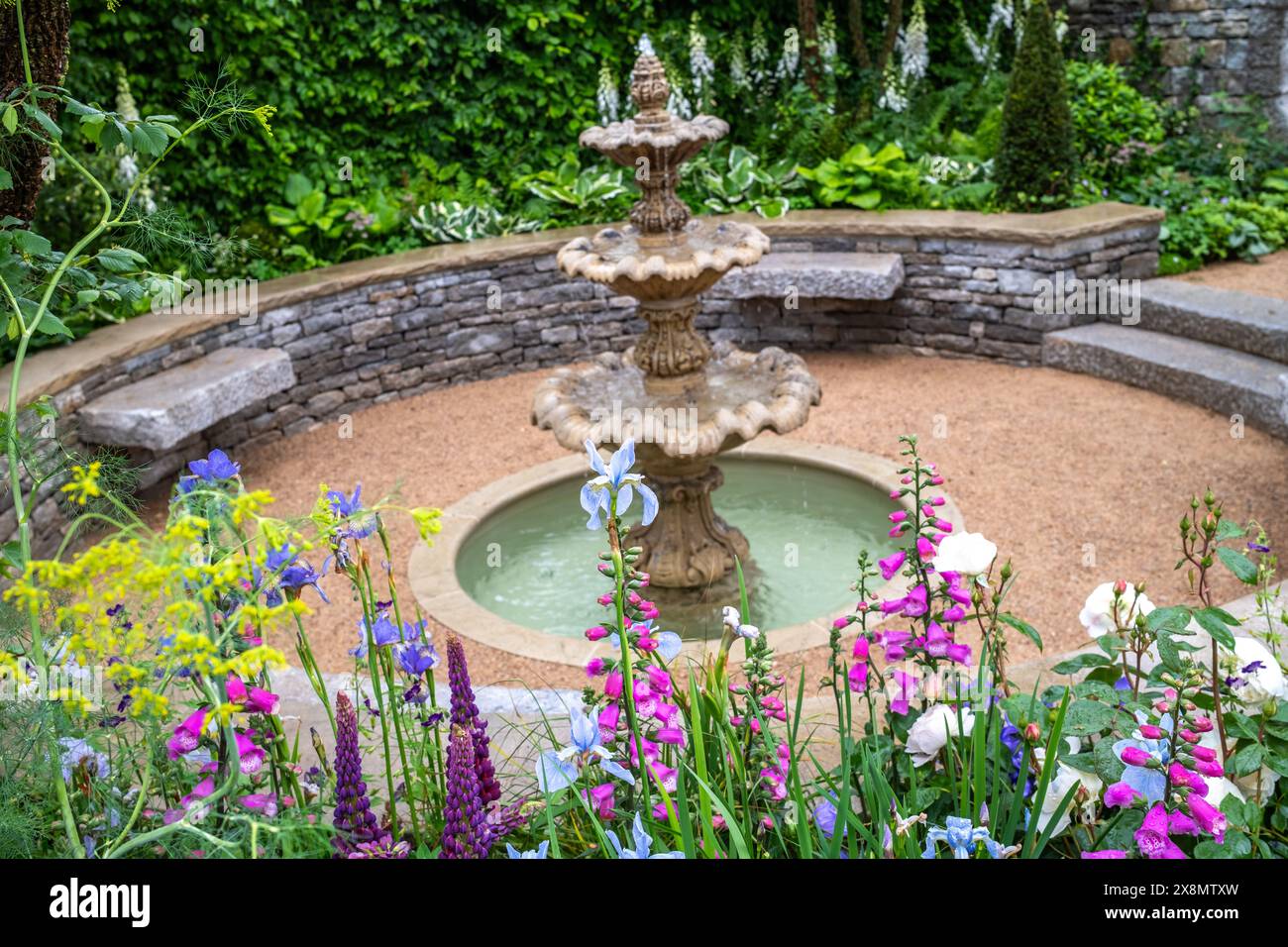 Selective focus on a flower garden with an ornate water feature behind ...