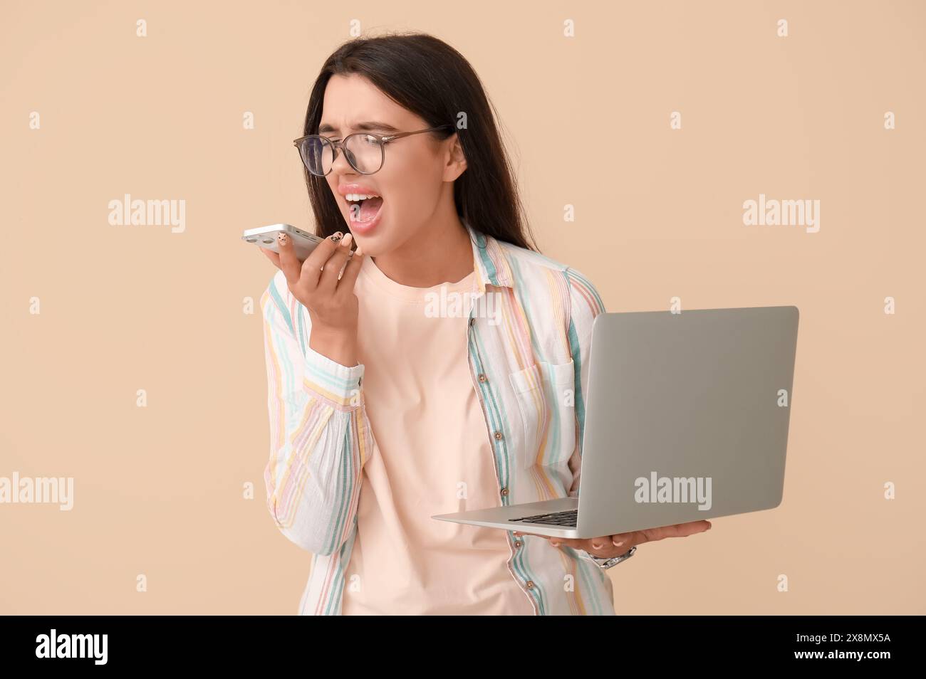 Angry screaming young female programmer with laptop talking by mobile ...
