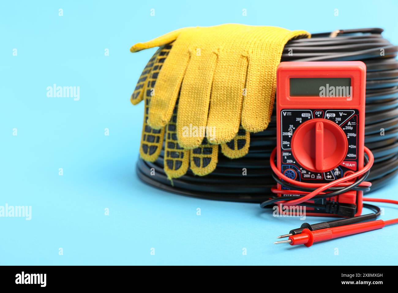 Multimeter, electric cable reel and gloves on color background Stock ...