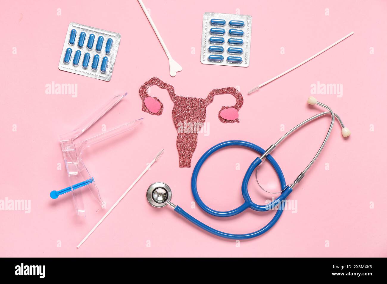 Paper uterus with pills, gynecological speculum and stethoscope on pink ...