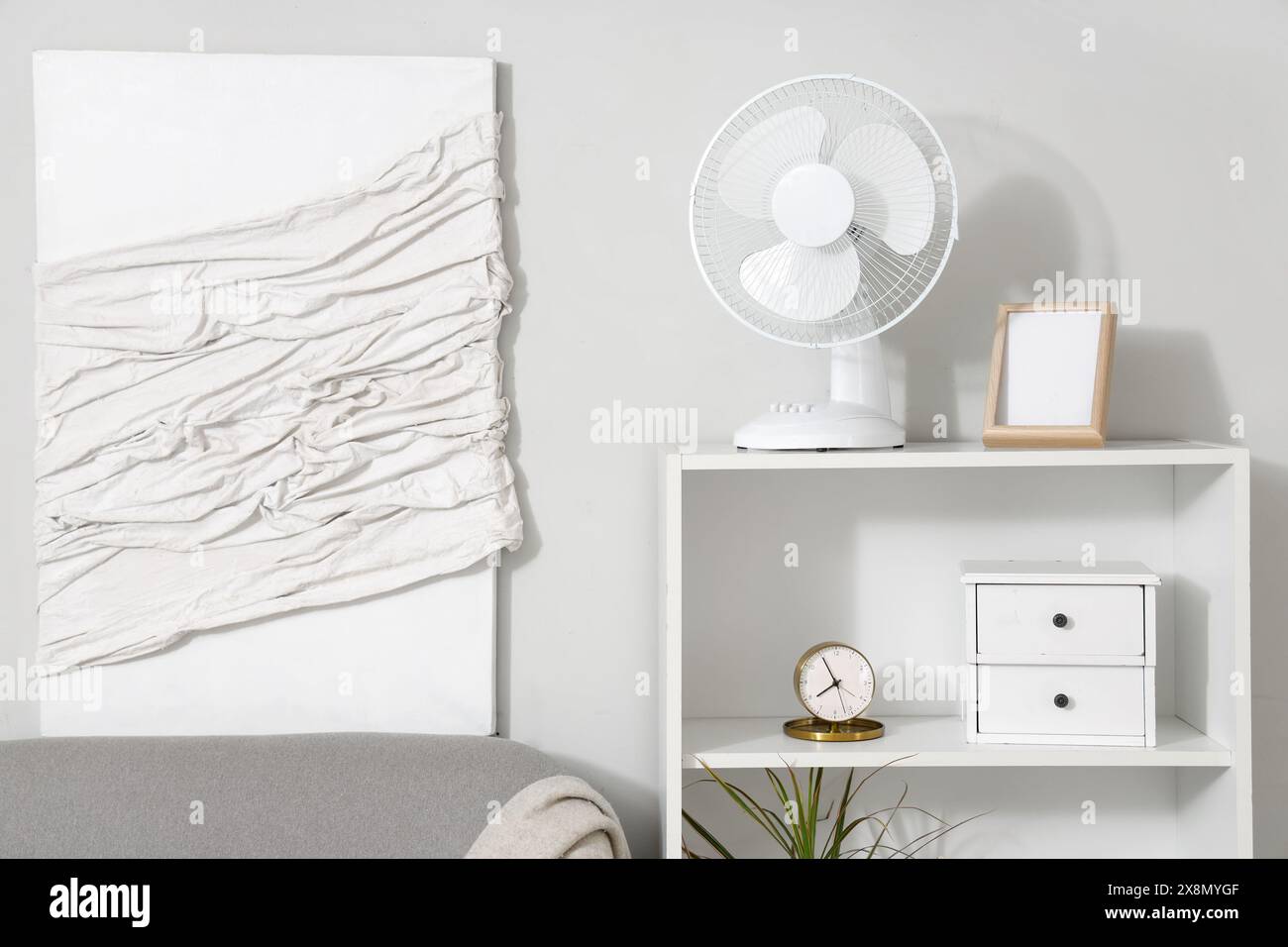 Interior of light living room with modern electric fan on shelving unit ...