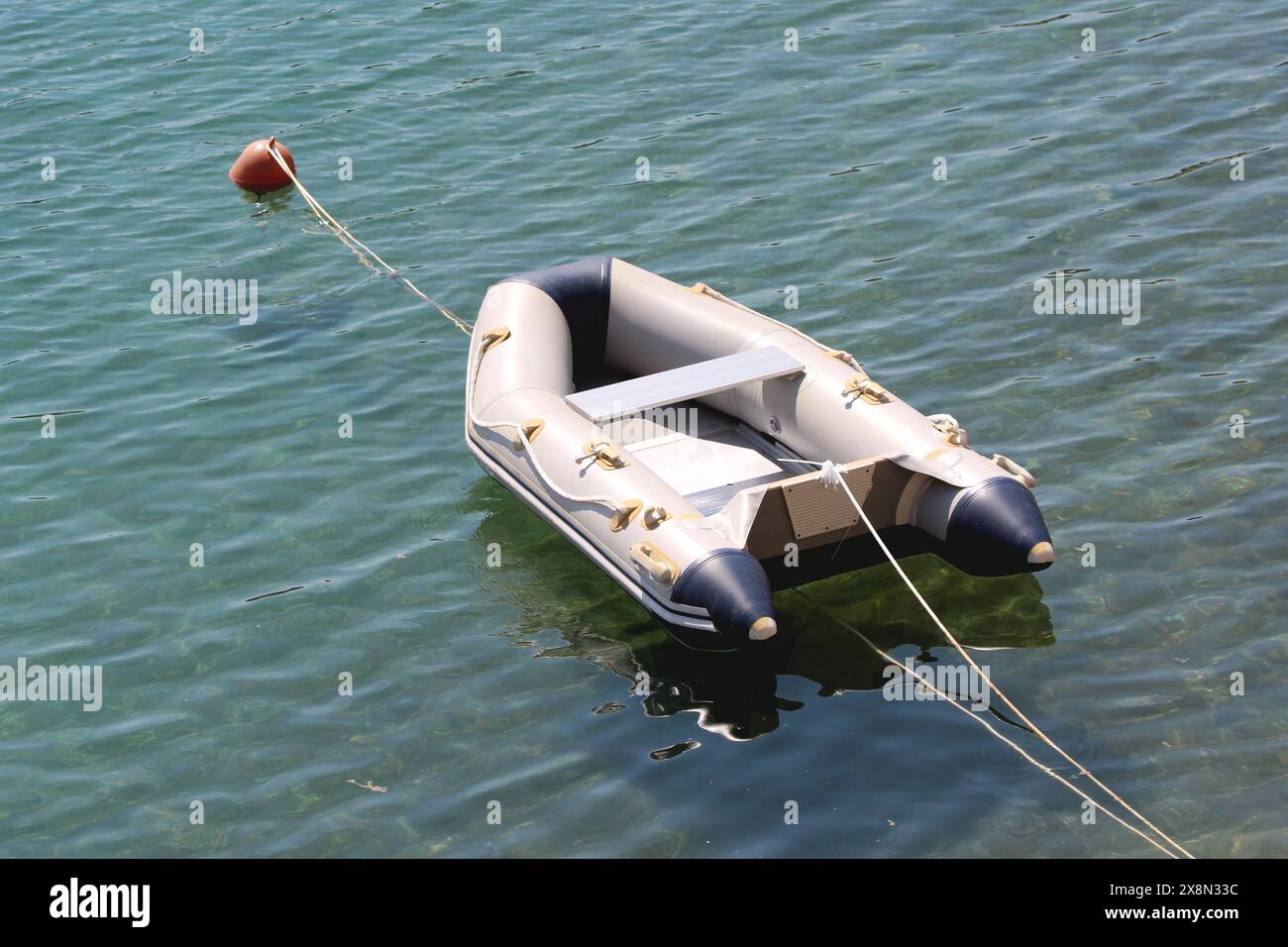 Small inflatable grey and dark blue rubber flatbeat dinghy boat with ...