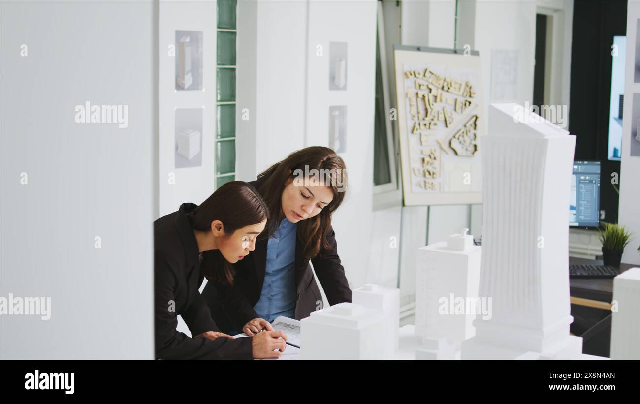 Two architects measuring building scale on blueprint, working together ...