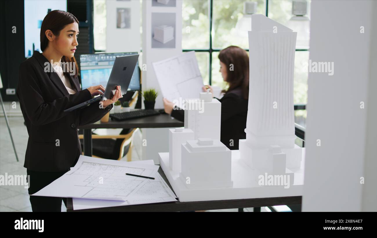 Asian contractor takes notes about 3d printed model on laptop ...