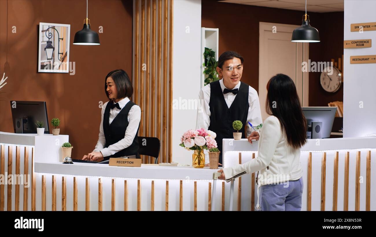 Front desk team staff welcoming hotel guest at reception, smiling and ...