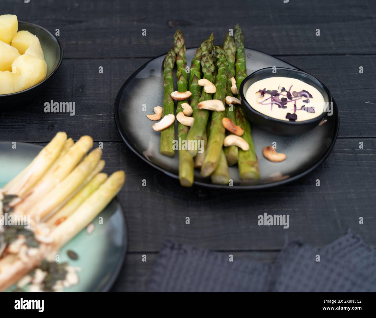 White and green asparagus served on dark plates with hollandaise sauce ...