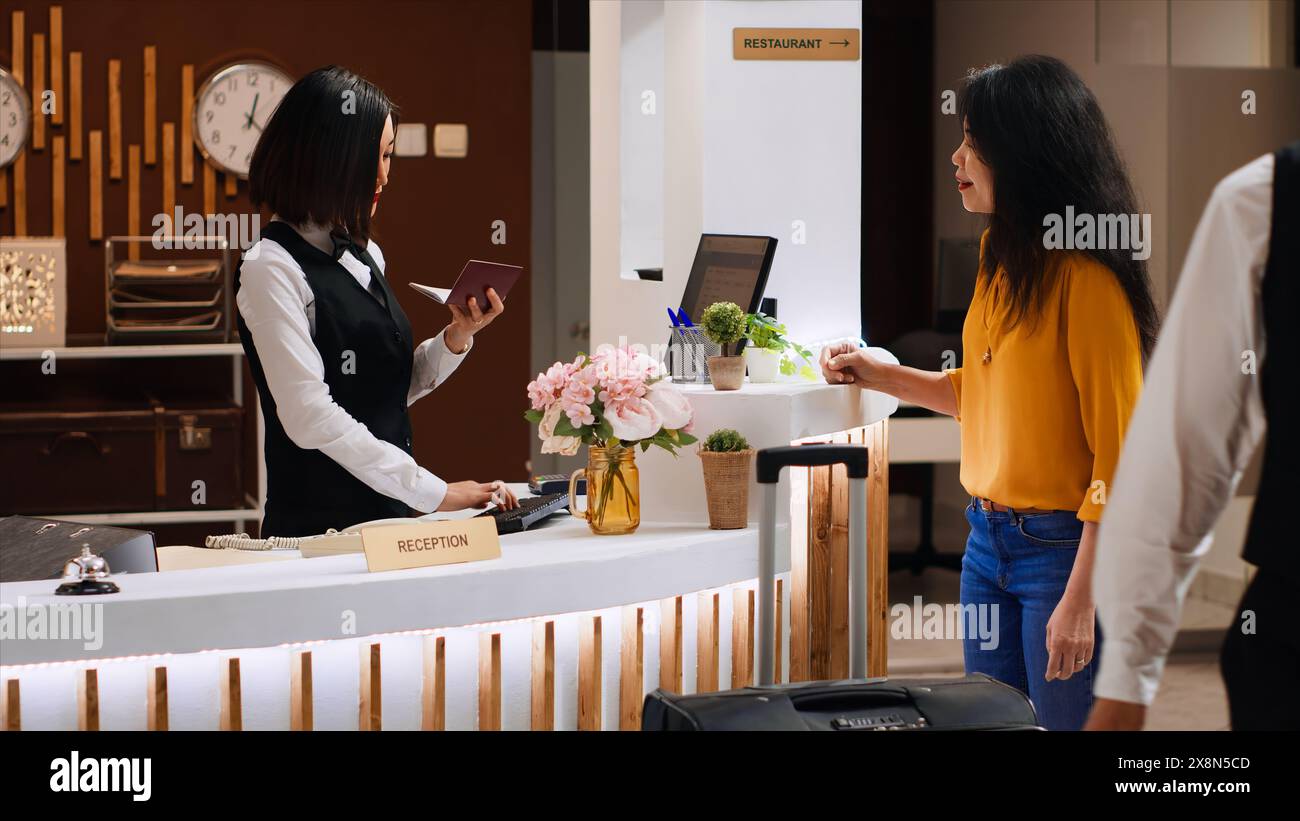 Asian hotel staff checking passport for id at check in, does ...