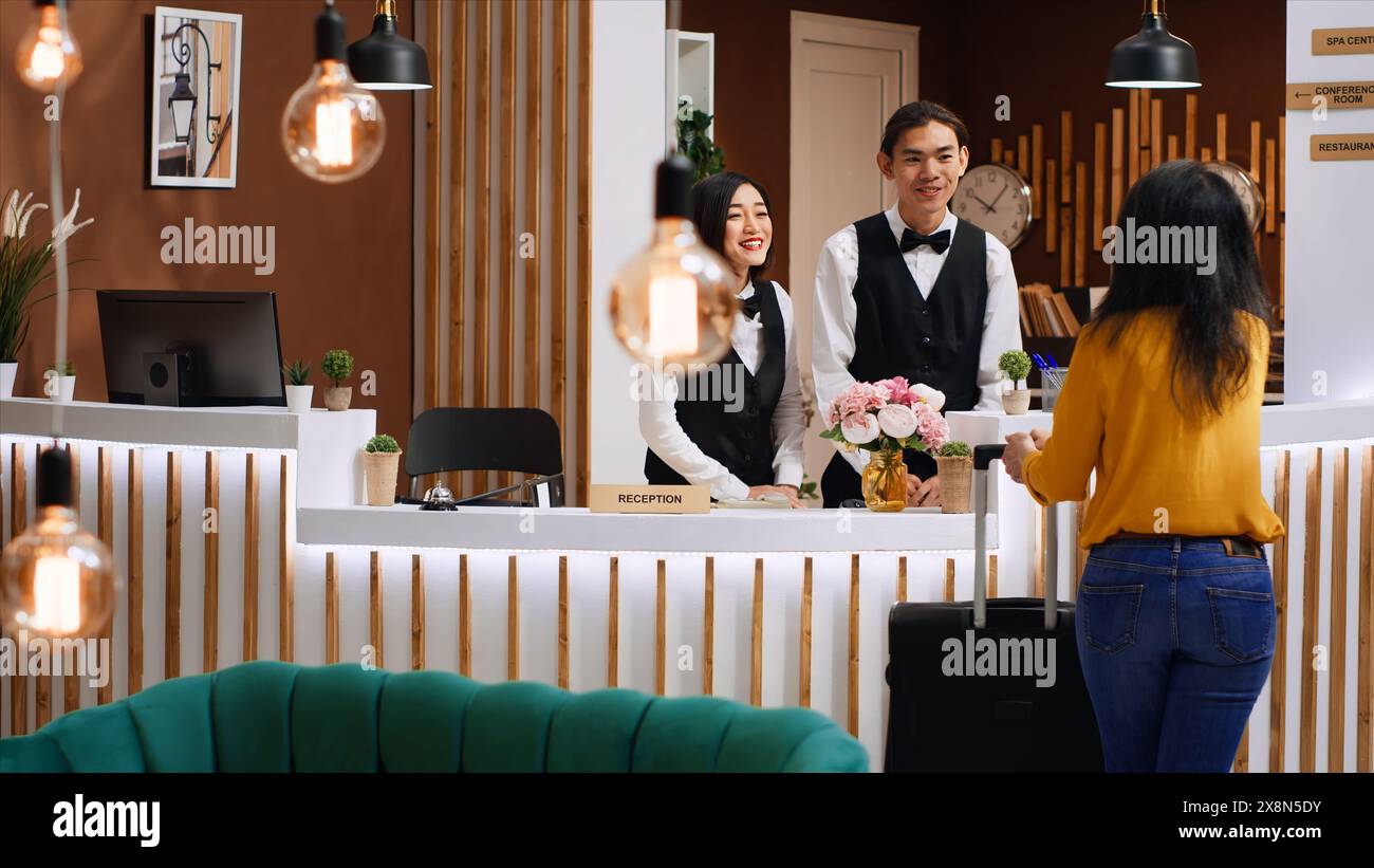 Front desk team greeting guest at five star hotel reception, welcoming ...