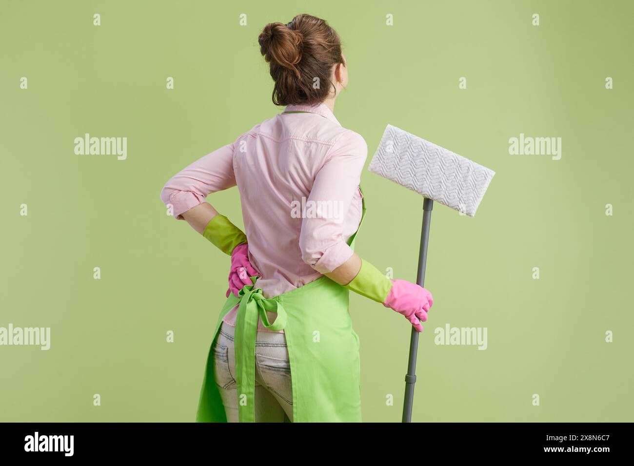 Spring cleaning. Seen from behind modern 40 years old woman in green ...