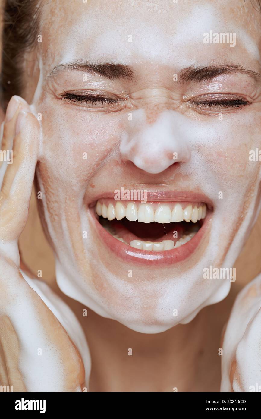 happy modern 40 years old woman with foaming facial cleanser washing ...