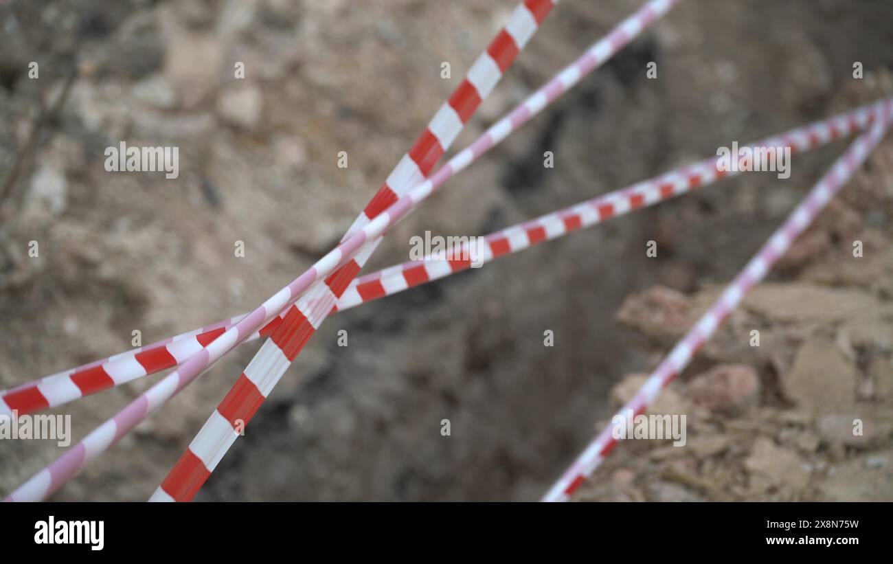 Red white barrier tape trenches. Focus on red and white barrier tape at ...