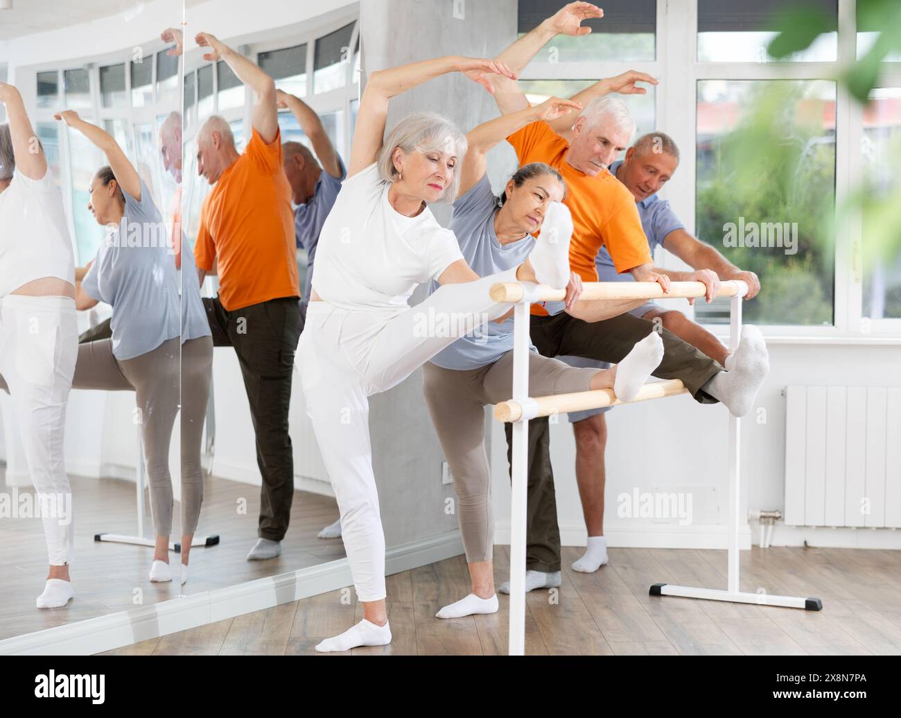 Ballet pose grand batman - elderly women and men at choreography lesson ...