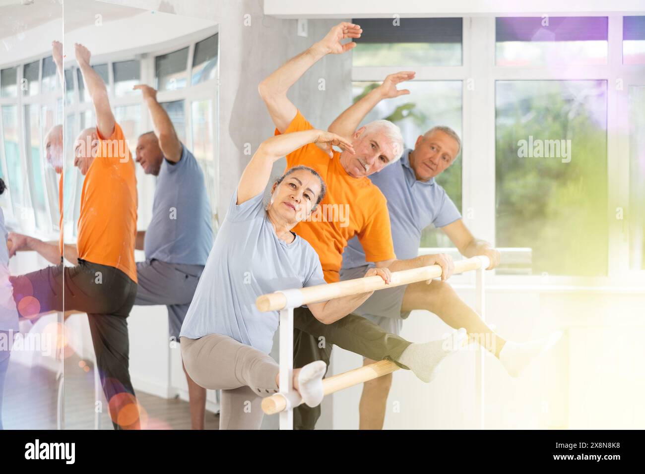 Ballet pose grand batman - elderly women and men at choreography lesson ...