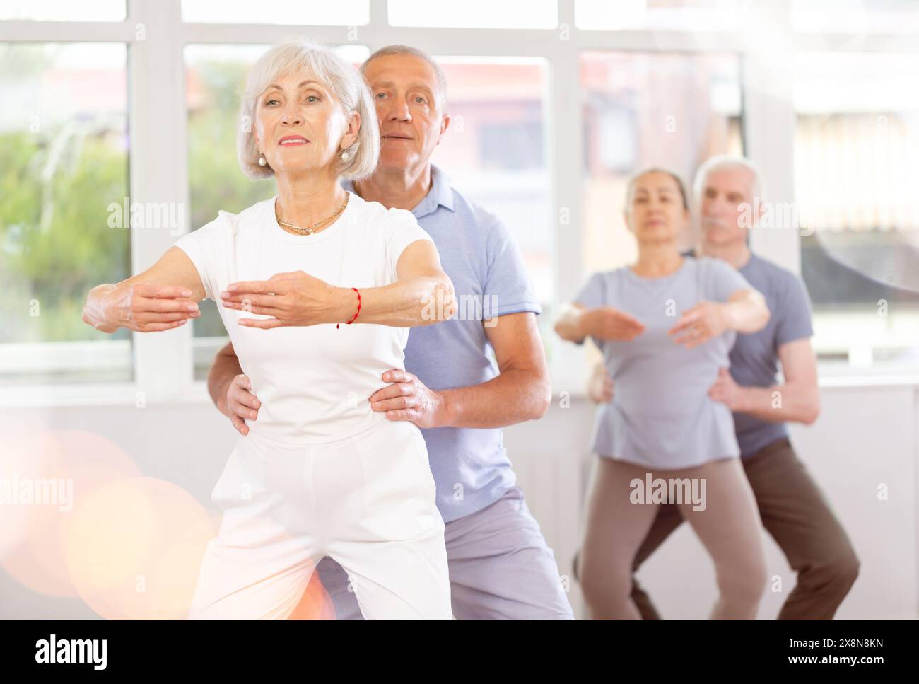 Mature woman practicing plie position in pair with man in dance studio ...