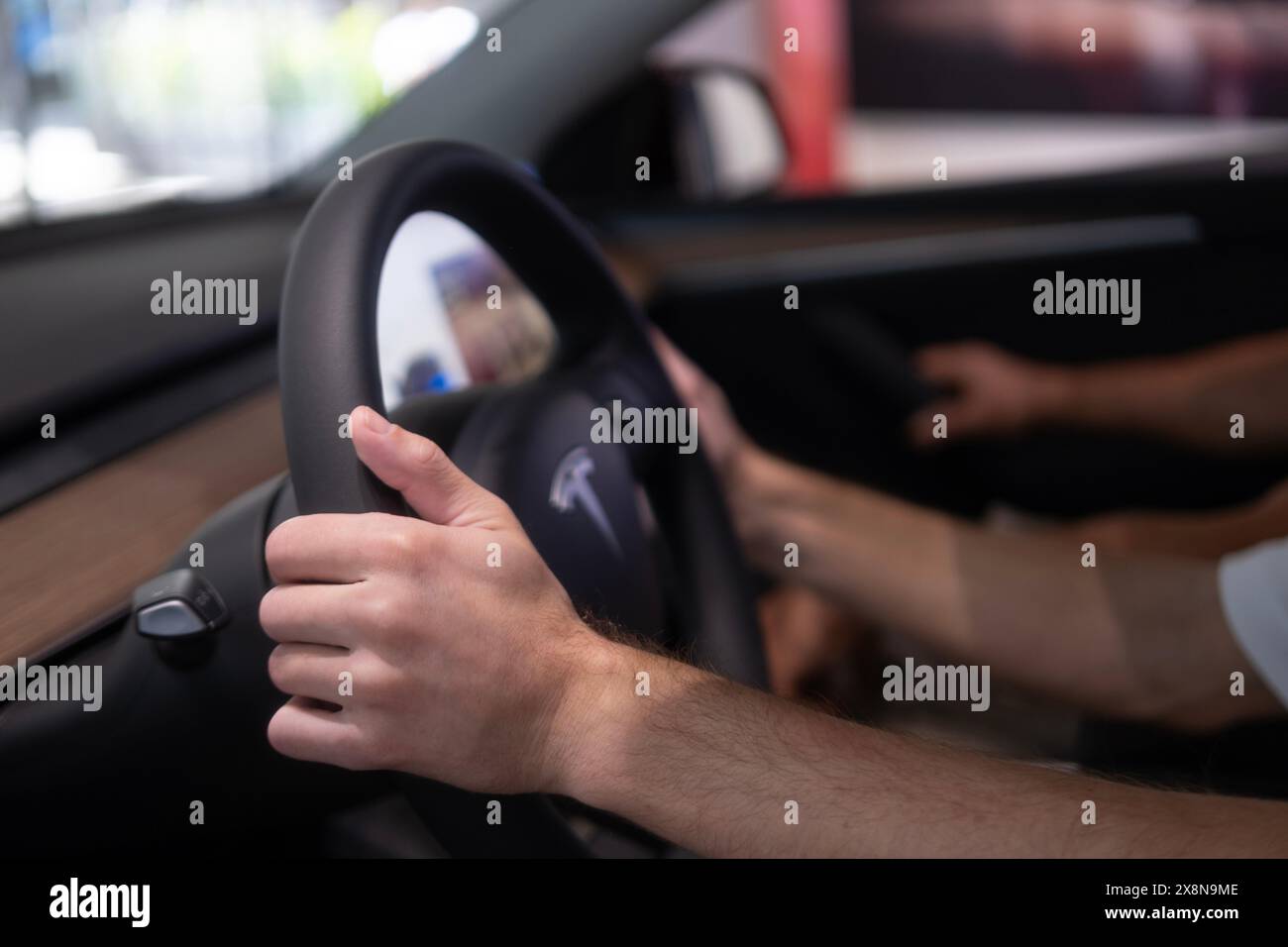 Behind steering wheel Tesla model Y electric car, male hands on Driver ...