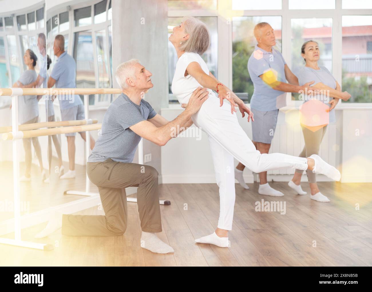 Mature man and woman practicing arabesque position of ballet in pair in ...
