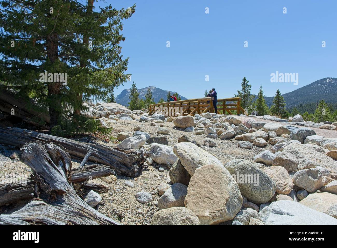 Tourists on timber footbridge over boulder strewn banks of Roaring river in Rocky Mountain ...