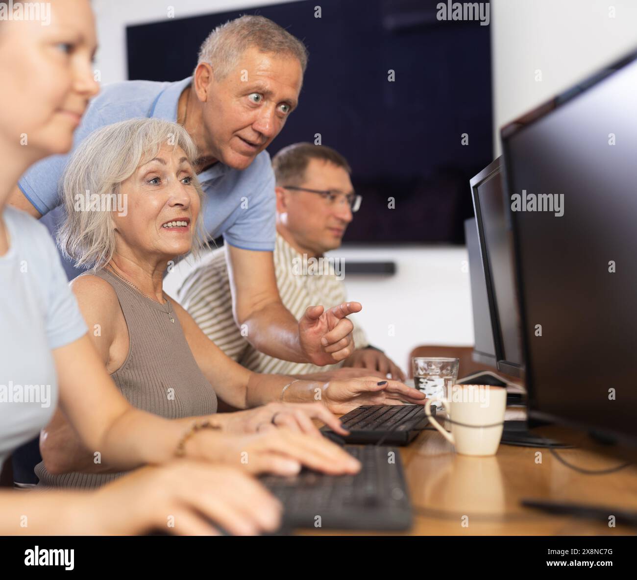Experienced teacher of computer class assisting enthusiastic woman ...