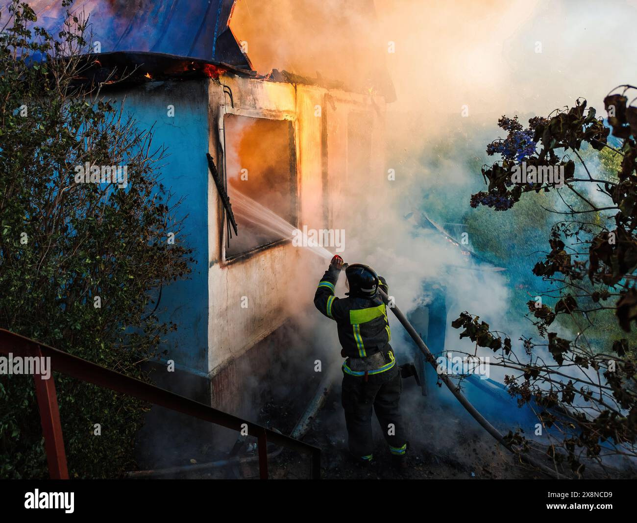 Firefighter extinguish fire in house using spraying hose Stock Photo ...