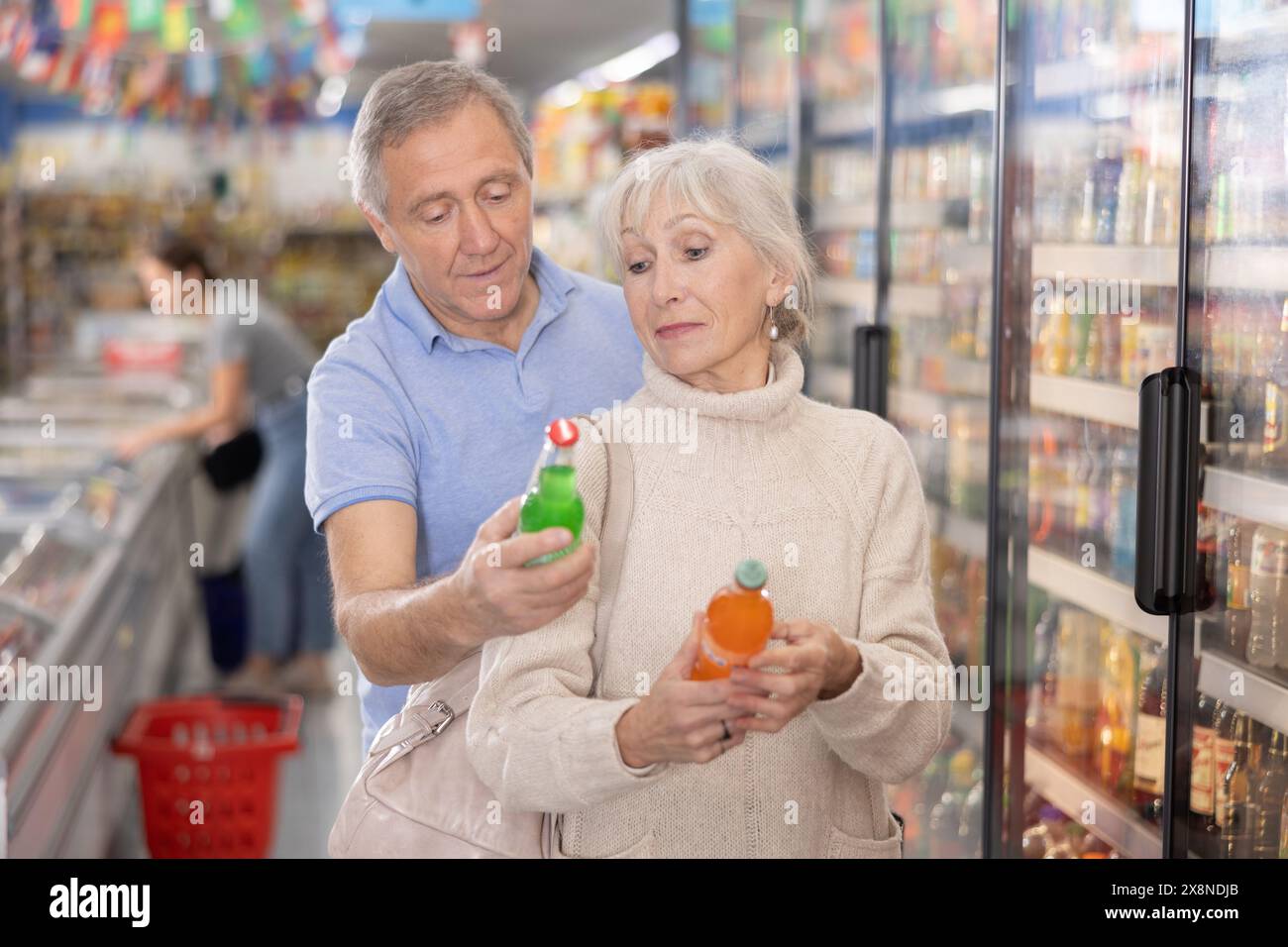 Man and woman purchasers choosing cool drink in supermarket Stock Photo ...