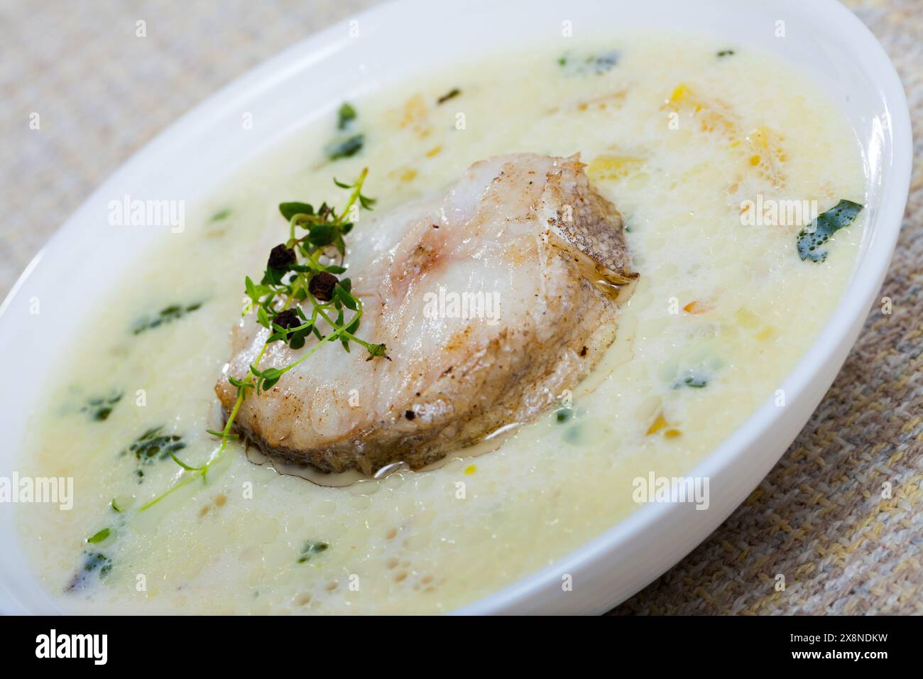 Boiled creamy soup with white fish pollock and greens at plate Stock ...