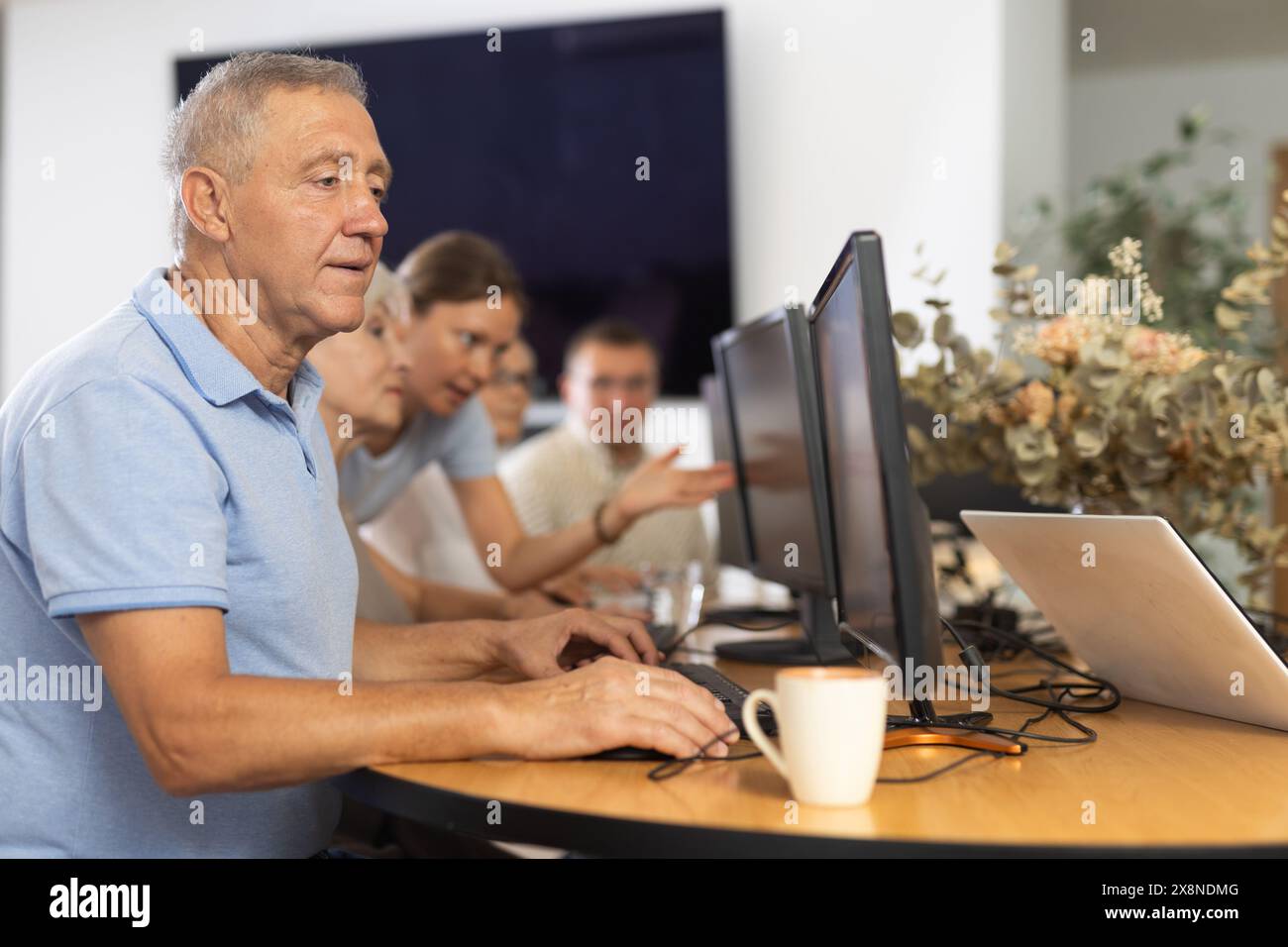 Elderly man taking computer lessons with group of elderly people in ...