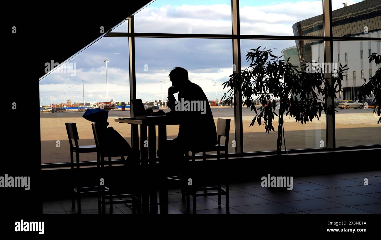 Businessman waiting for boarding at the airport and looking through ...