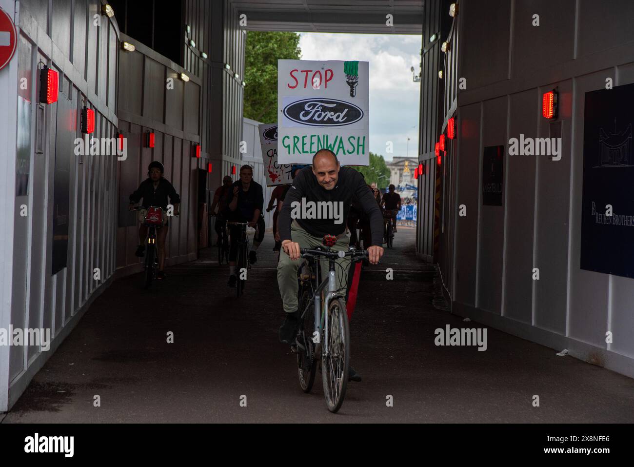 London, UK. 26th May, 2024. A cyclist rides through with a placard ...