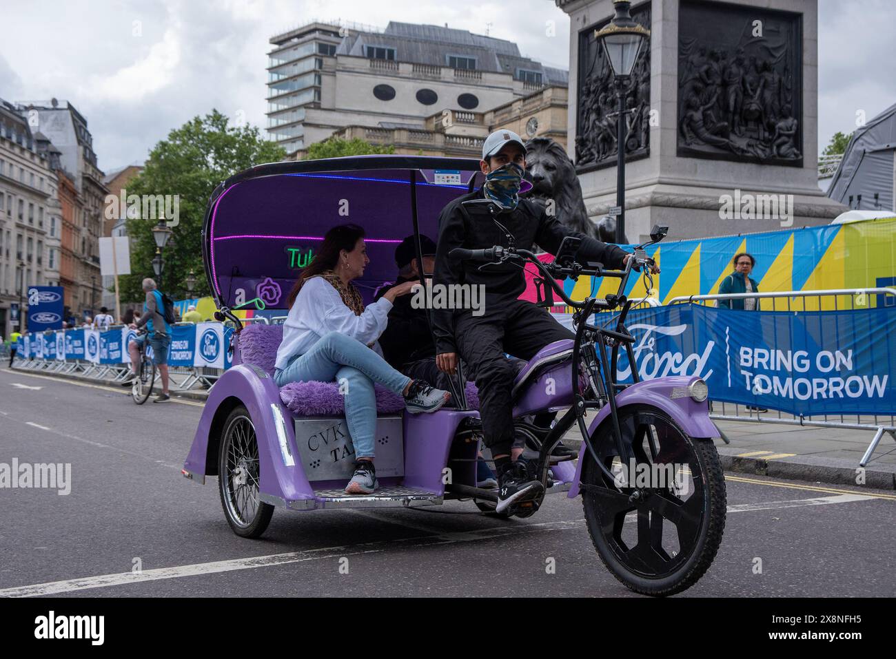 A tuk tuk driver drives through with costumers at the Trafalgar Square ...