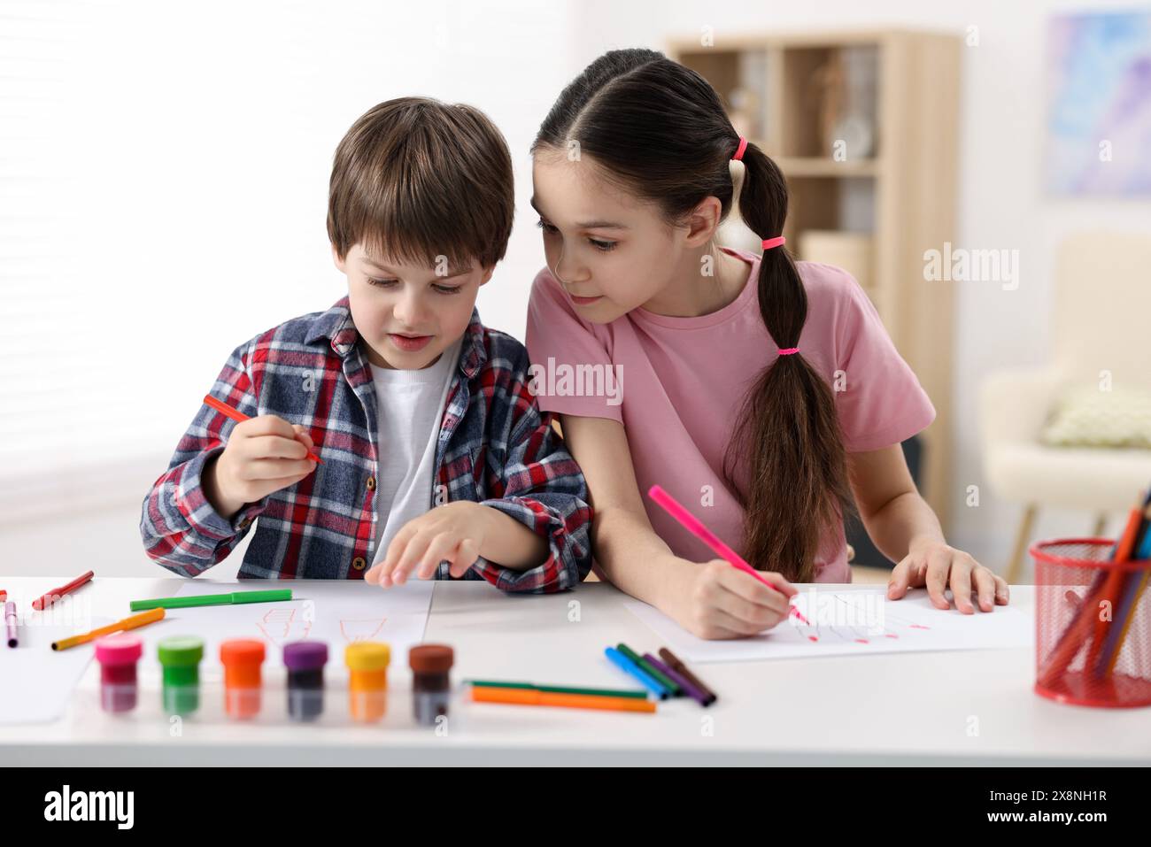 Happy brother and sister drawing at white table in room Stock Photo - Alamy