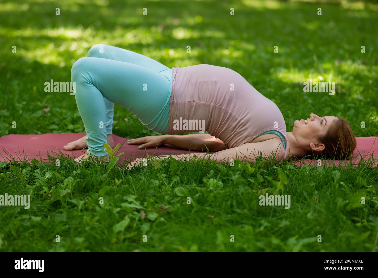 Pregnant caucasian woman doing yoga in the park. Prenatal shoulder ...