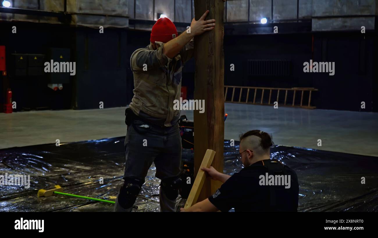 Assembly of wooden stage construction by young builders. Media. Men ...