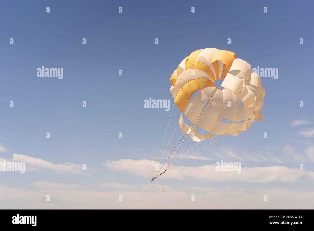 The parachute is fully inflated, showcasing vivid yellow and white ...
