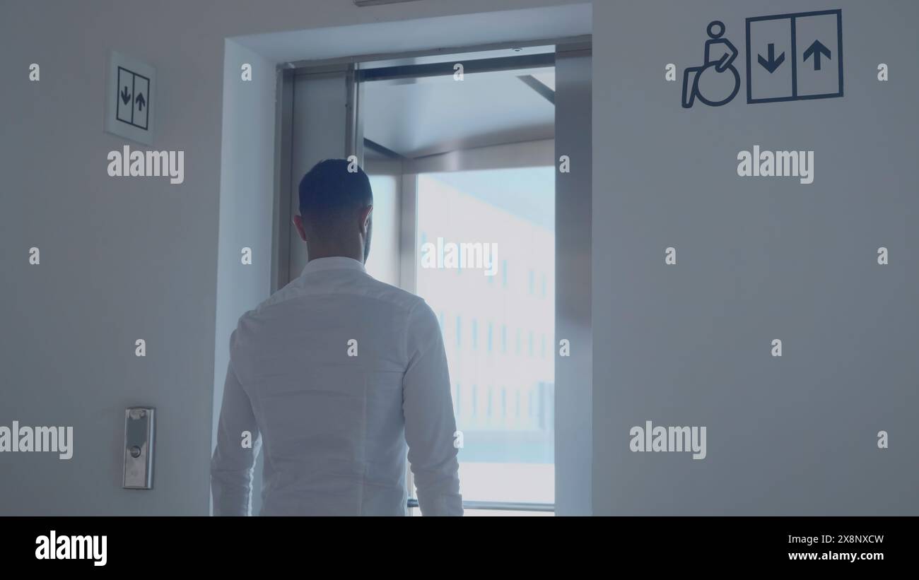 Man enters elevator with window. Media. Rear view of man entering light ...