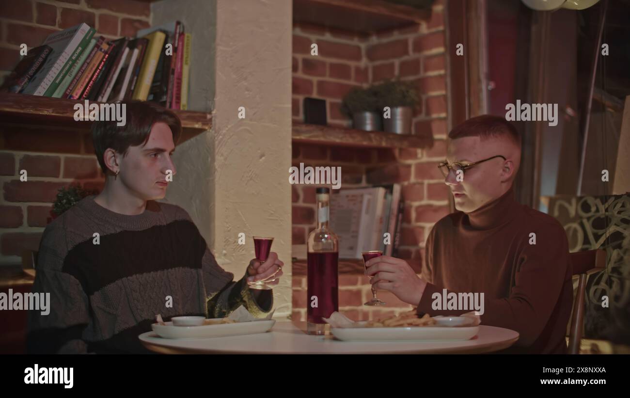 Two young male friends spend time together at restaurant or bar. Media ...