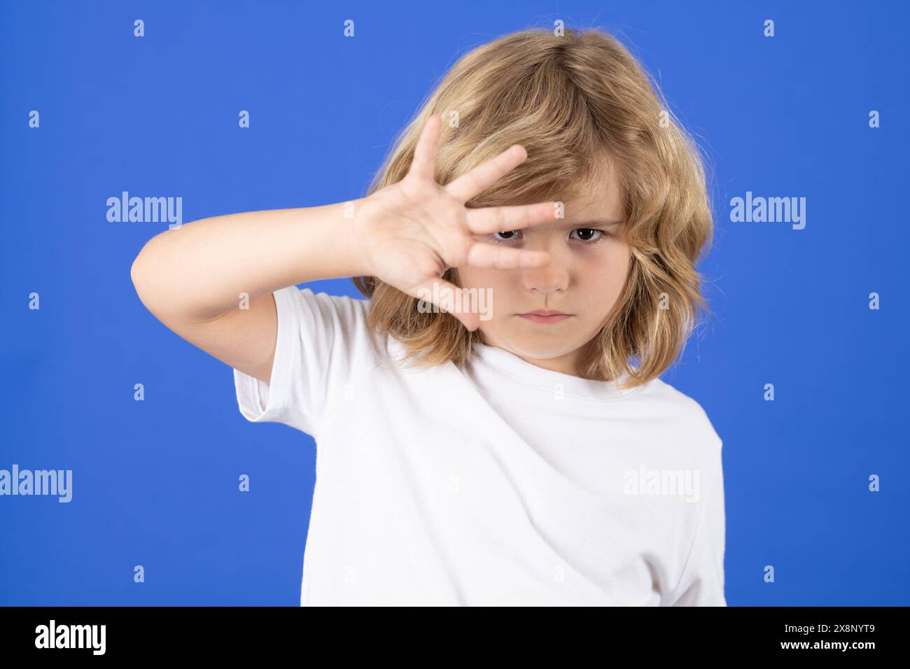 Child boy making stop gesture on isolated blue background. Kid showing ...