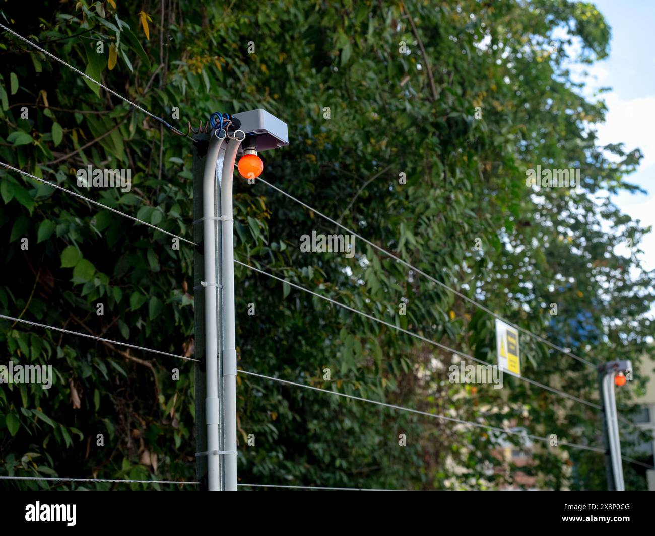 Red warning light bulb installed on light poles on wire electric fence ...
