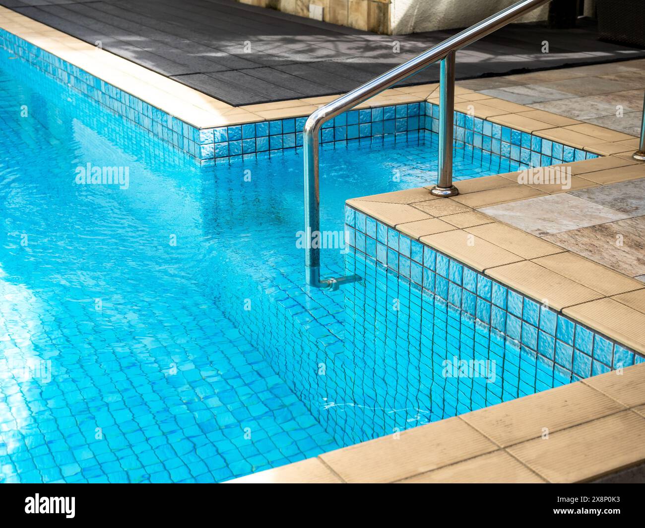 Chrome metal grab bar, clear water surface on swimming pool with stair ...