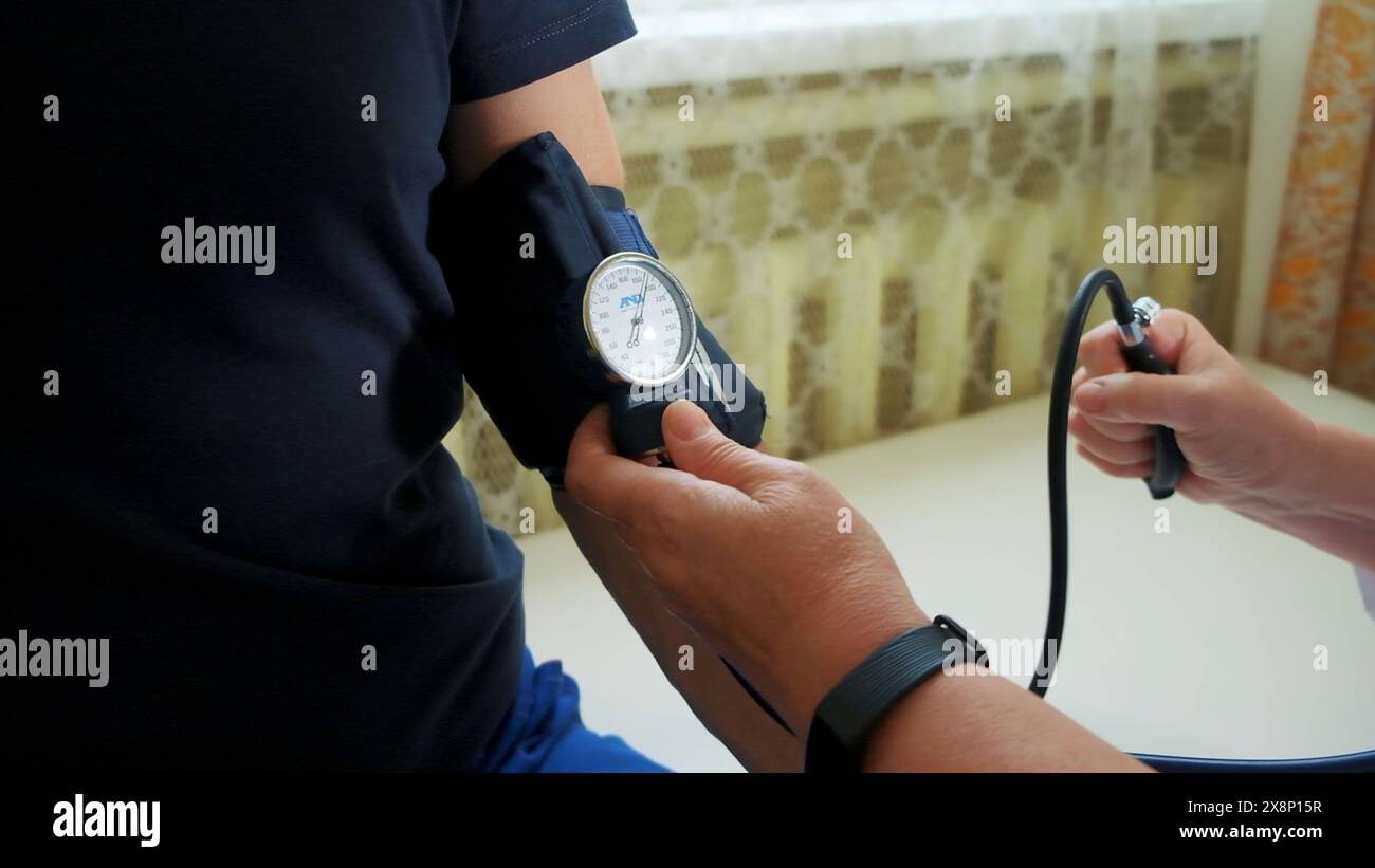 Doctor uses mechanical tonometer to check body pressure of a male ...