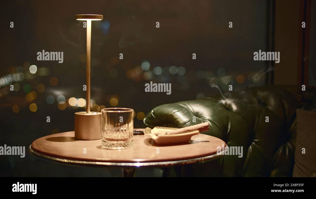 Smoking cigar on table in restaurant. Media. Close-up of smoking cigar ...